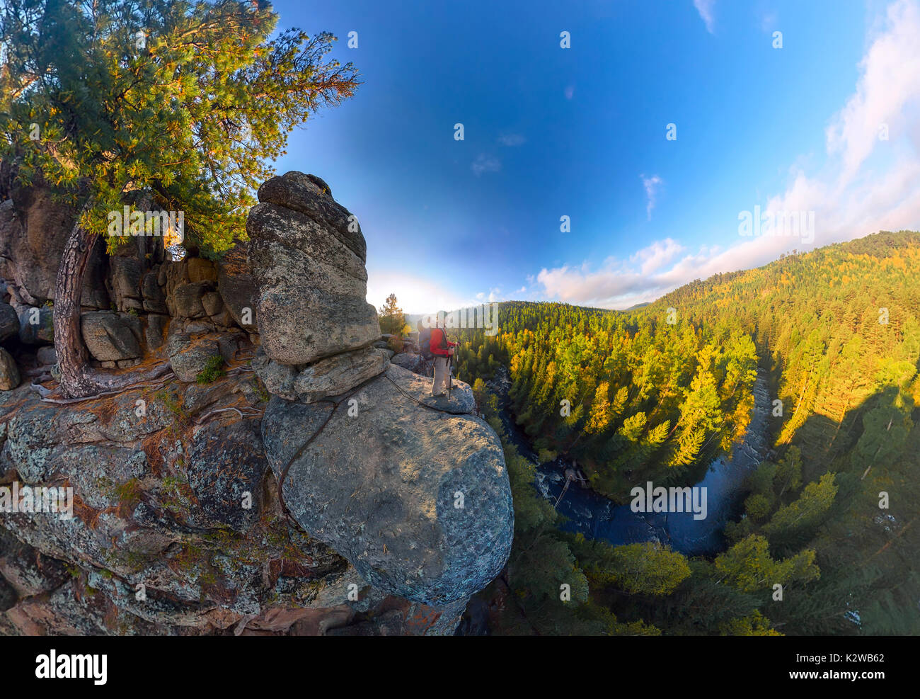 Backpacker on top of a rock fall at dawn. Wide angle aerial panorama ...