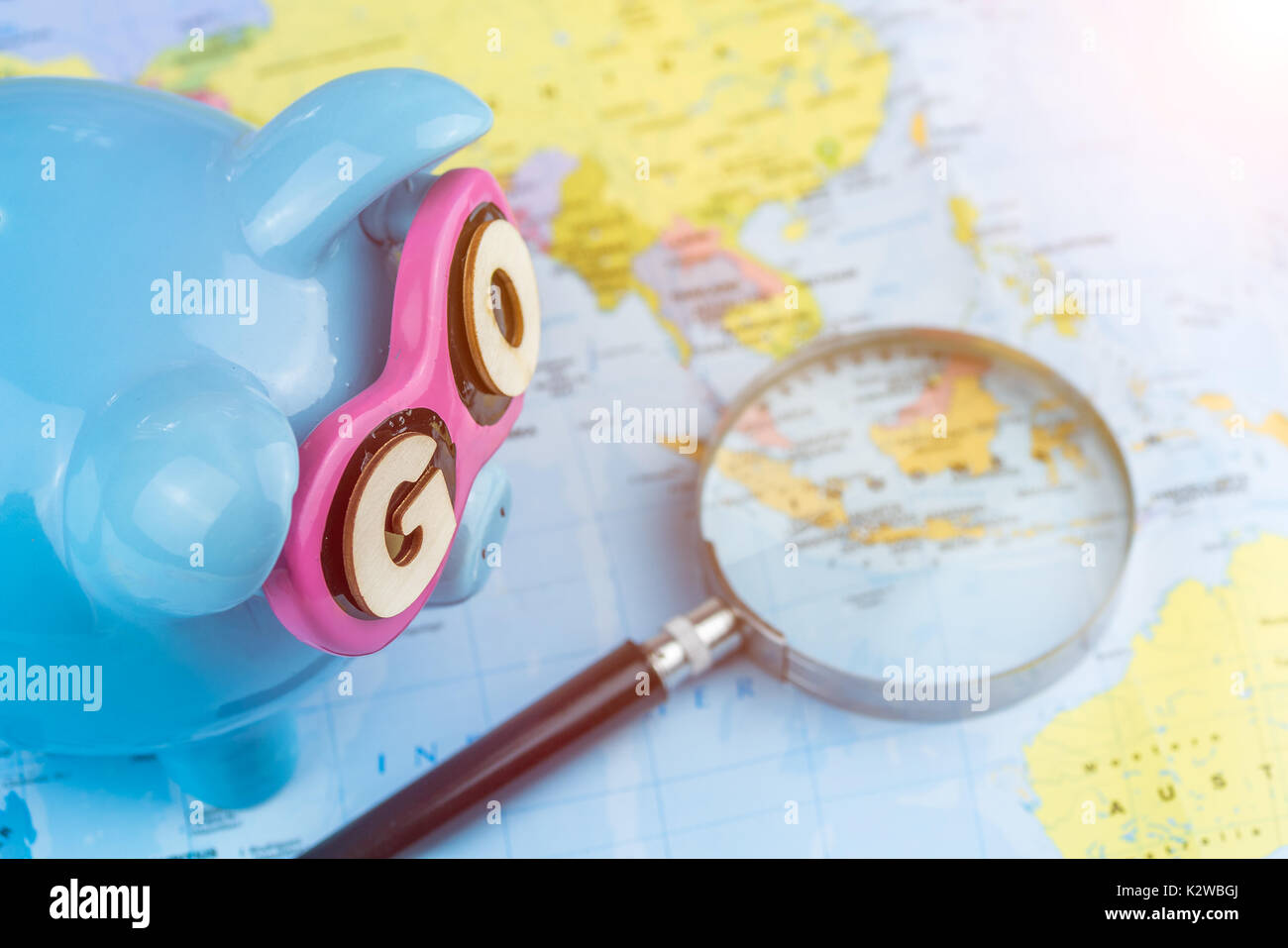 Magnifier laying on the defocused map. Saving piggy bank is ready for ... Magnifier laying on the defocused map. Saving piggy bank is ready for ...