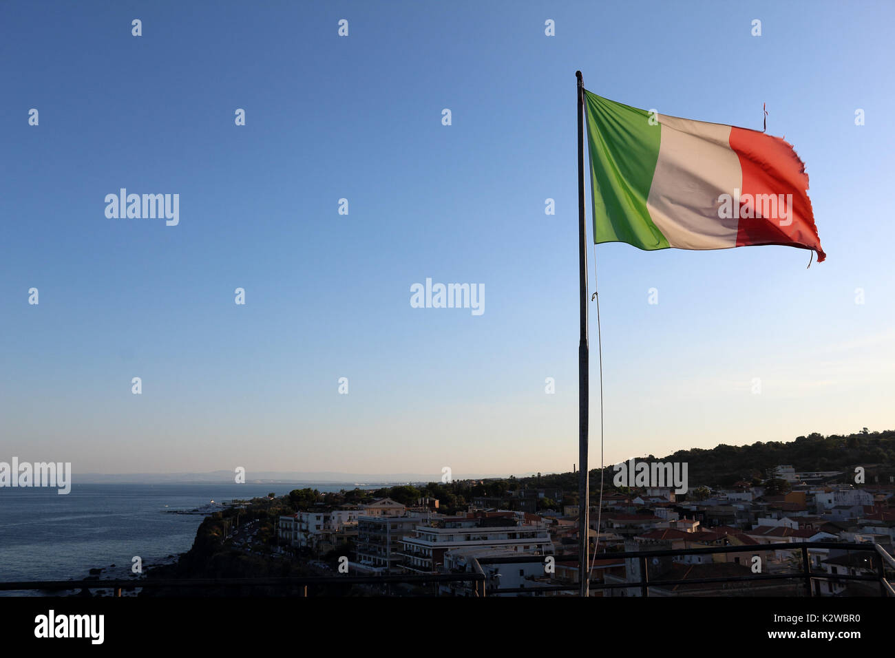 Italian flag flying over a town in summer, with clear blue sky behind ...