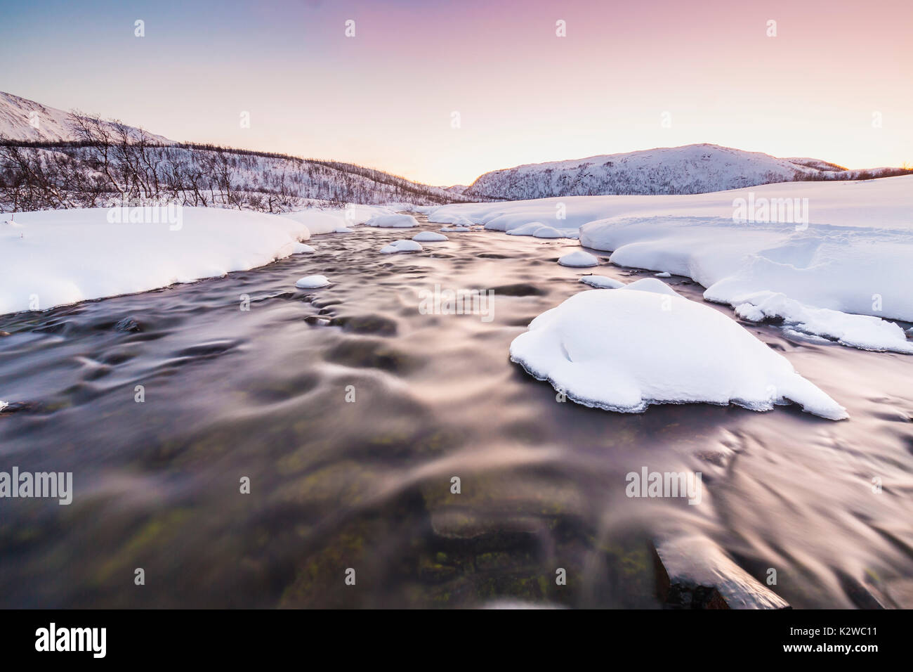 A little water stream with rocks on the foreground with a arctic, snowy ...