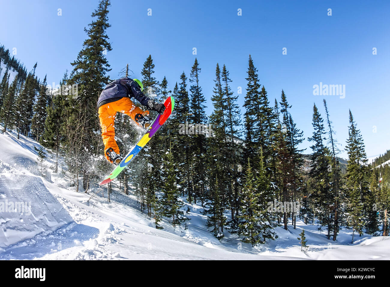 Snowboarder freerider jumping from a snow ramp in the sun on a ...
