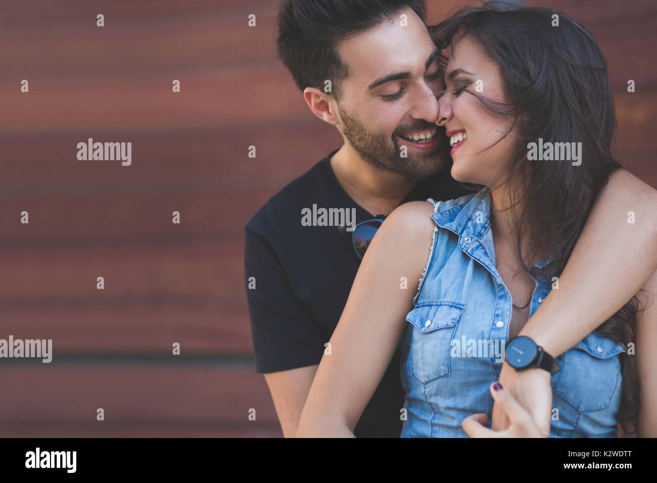 Portrait of happy couple cuddling together touching each other nose ...