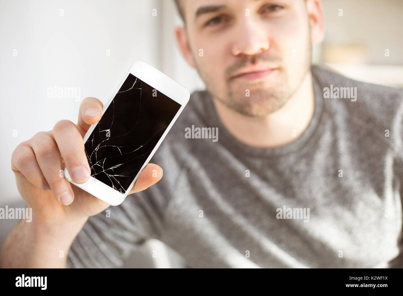 Sad man showing crashed mobile phone with touch screen Stock Photo - Alamy