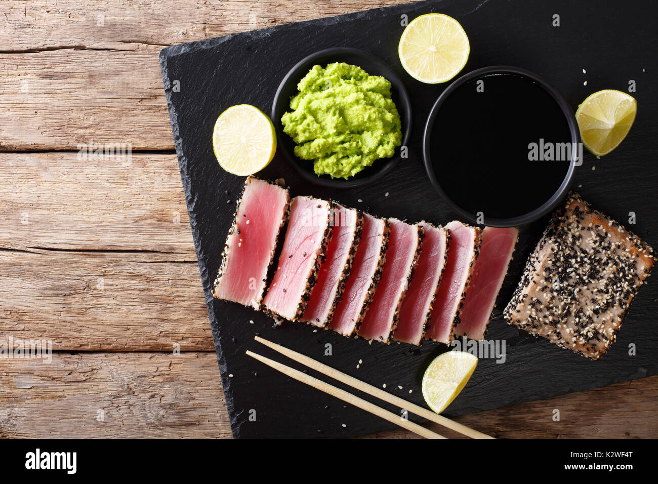 Stone slate tray with sliced tuna steak fried in sesame seeds closeup ...