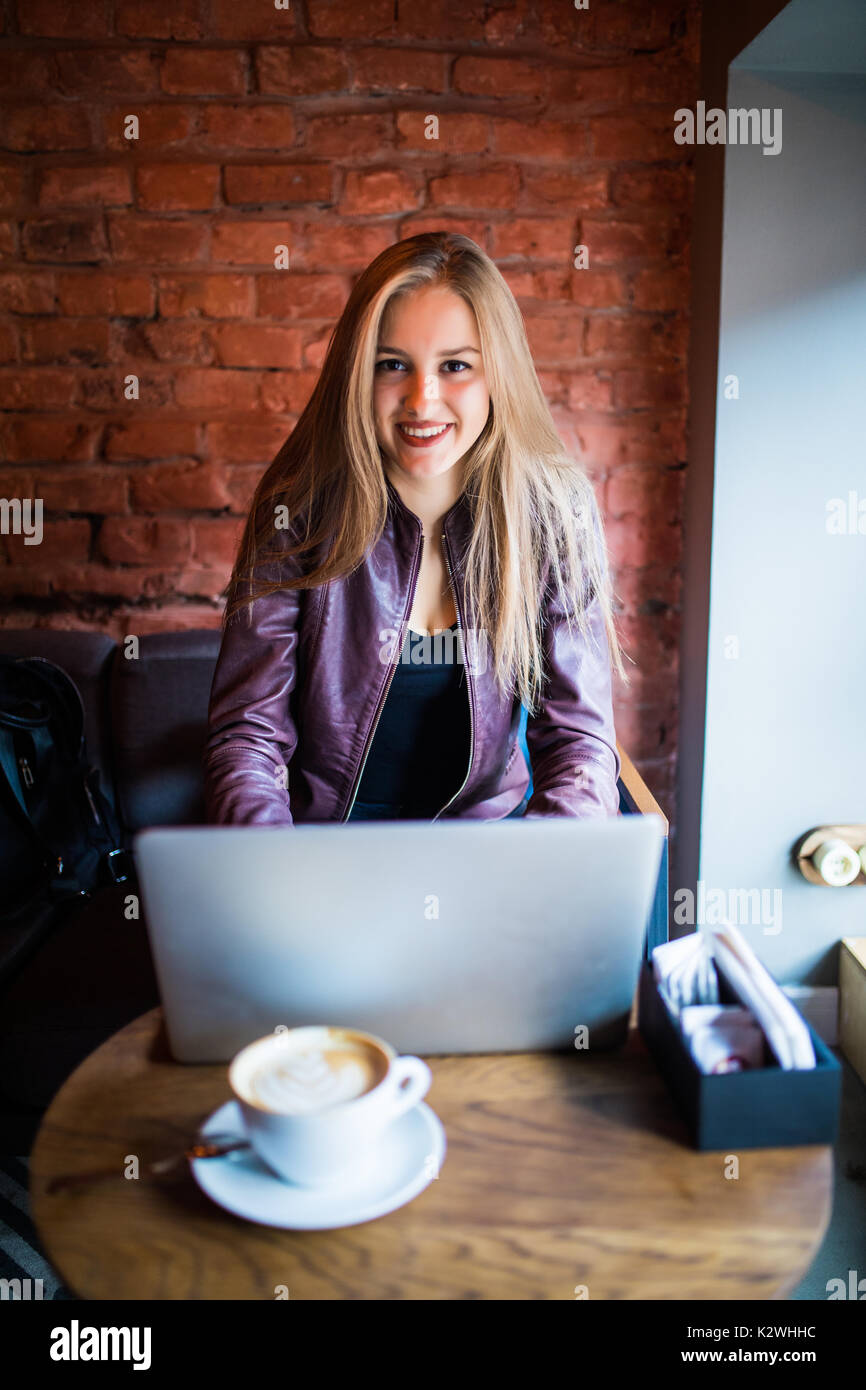 Beautiful woman dreaming about something while sitting with portable net-book in modern cafe bar ...