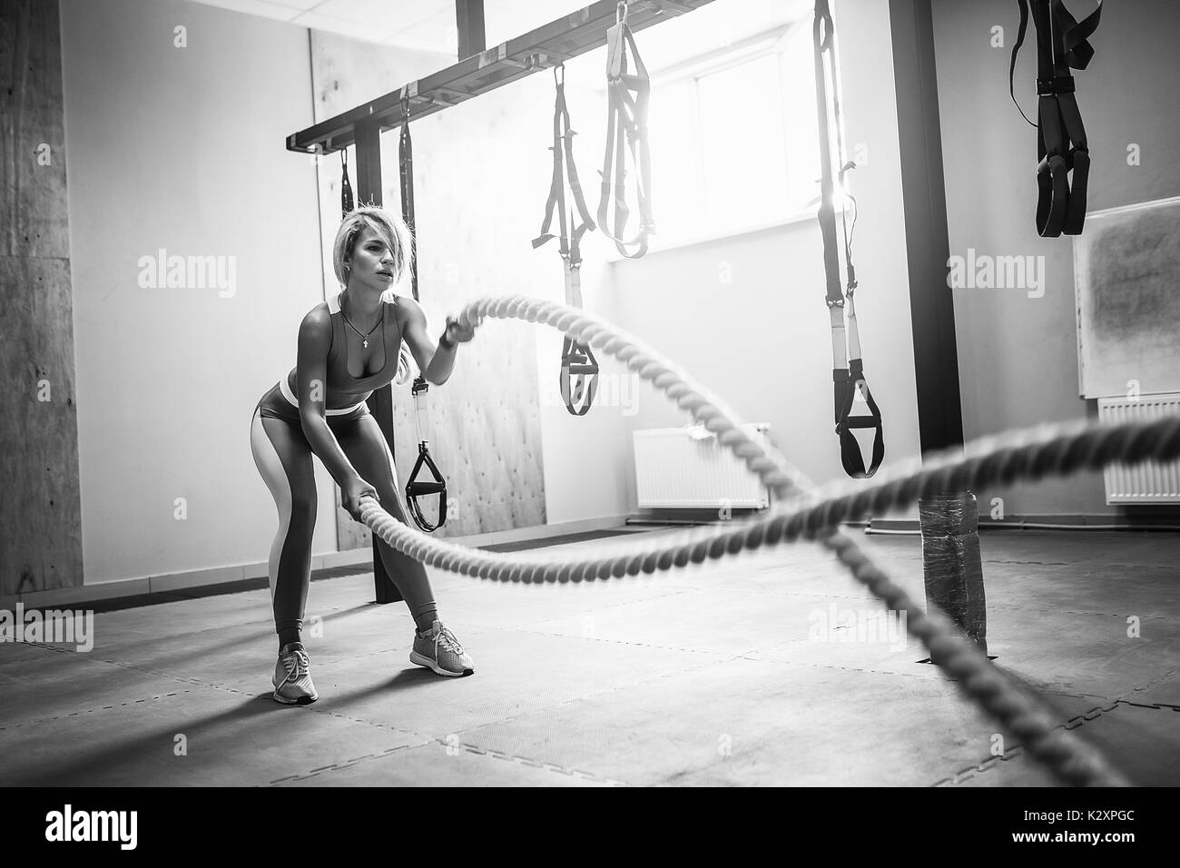 Woman with battle ropes exercise in the fitness gym. Young female ...