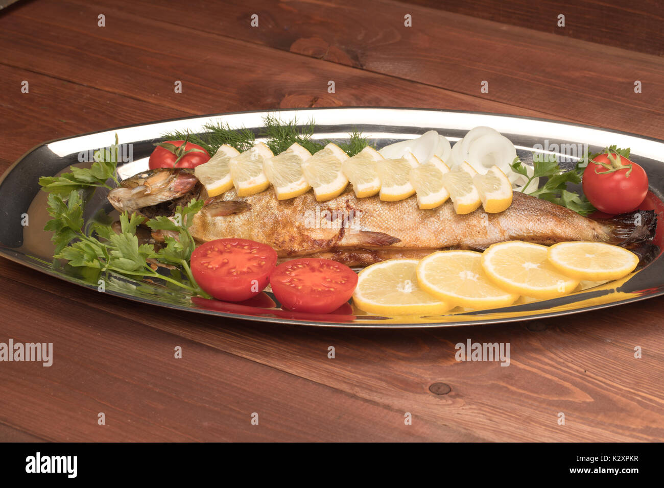 fish baked in foil on a tray with lemon greens and spices Stock Photo ...