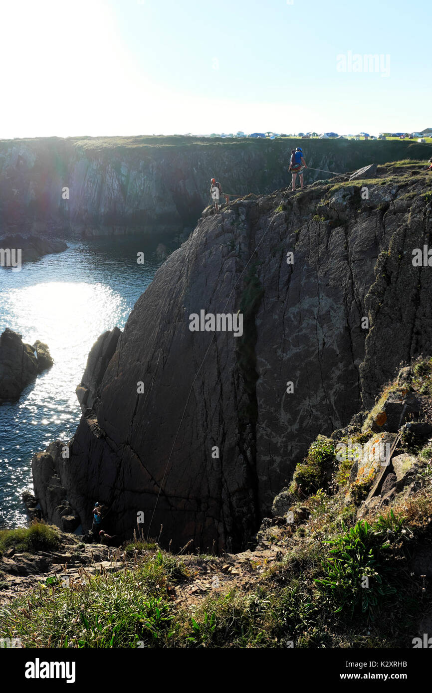 A vertical view climbers climbing on rocks on Pembrokeshire Coast near ...