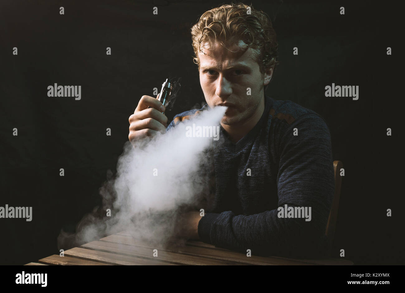 Isolated young man holding and vaping an electronic cigarette or e cig ...