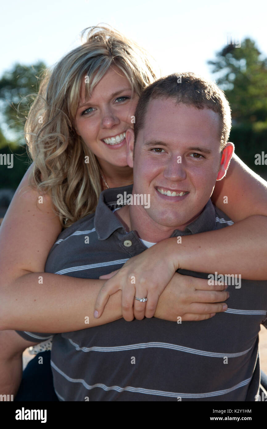 beautiful young engaged couple piggy back hug Stock Photo - Alamy