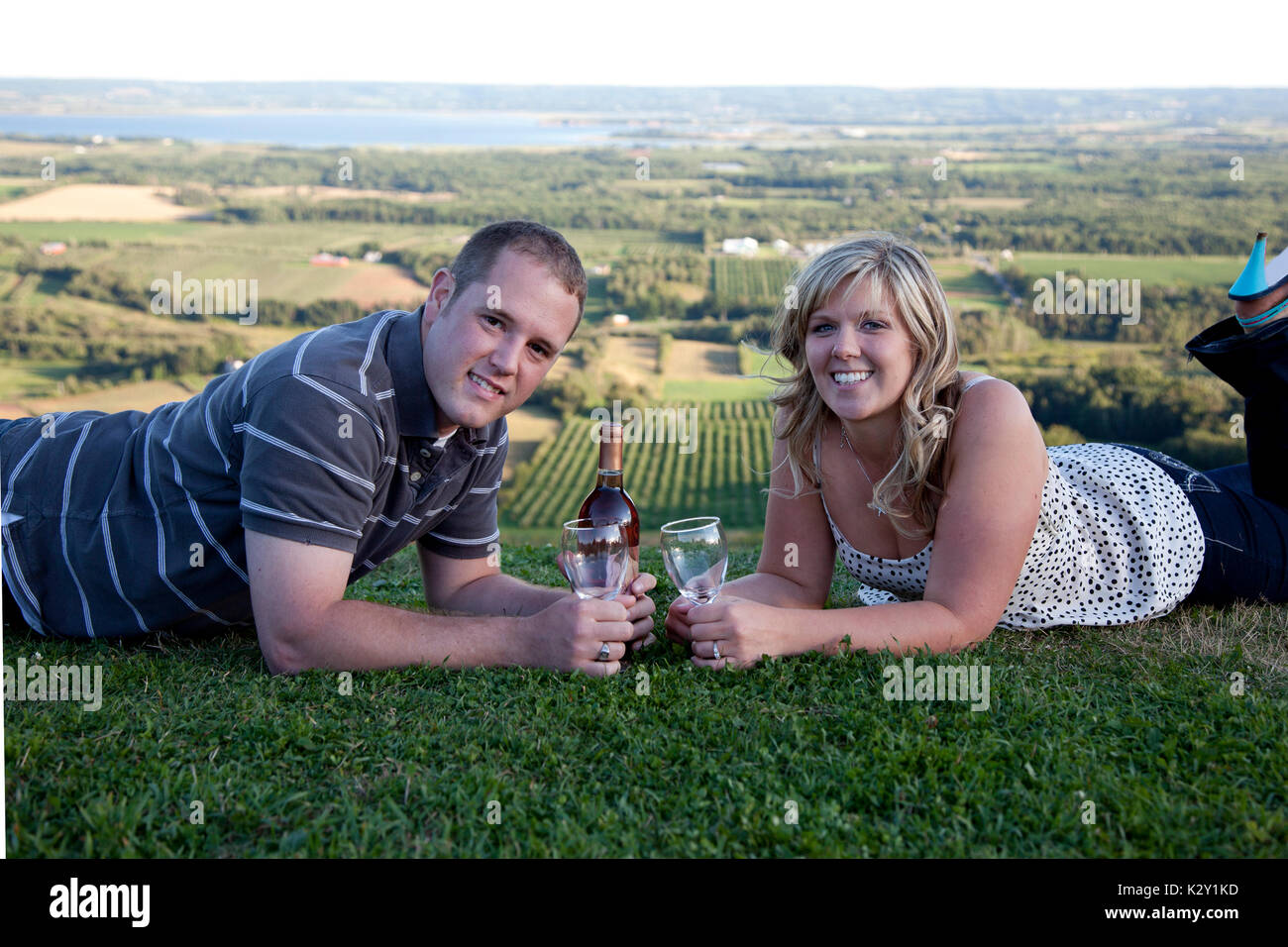 beautiful young couple lay on grass wine glasses celebrate their ...