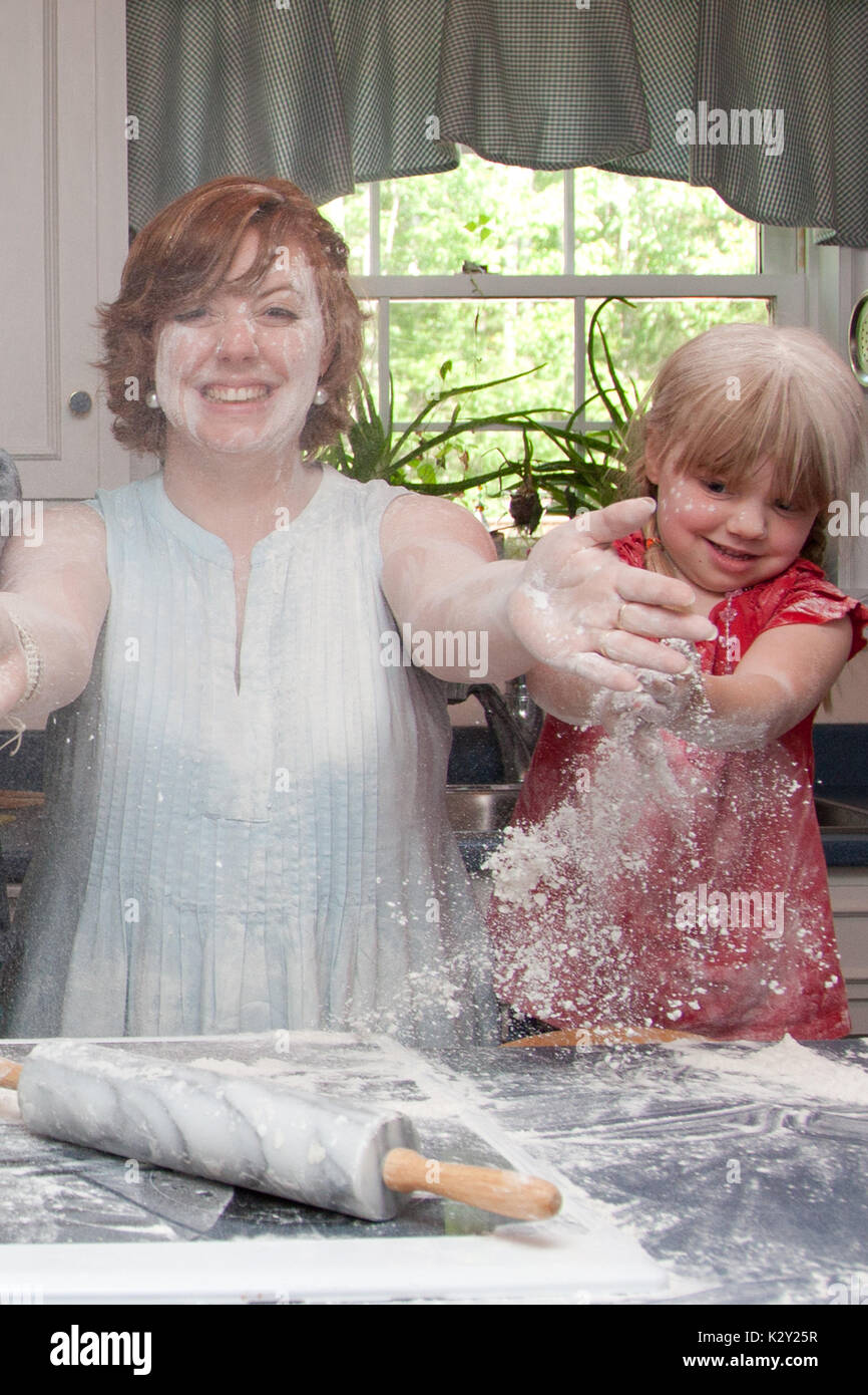 mother and a daughter having fun playing with flour in the kitchen ...