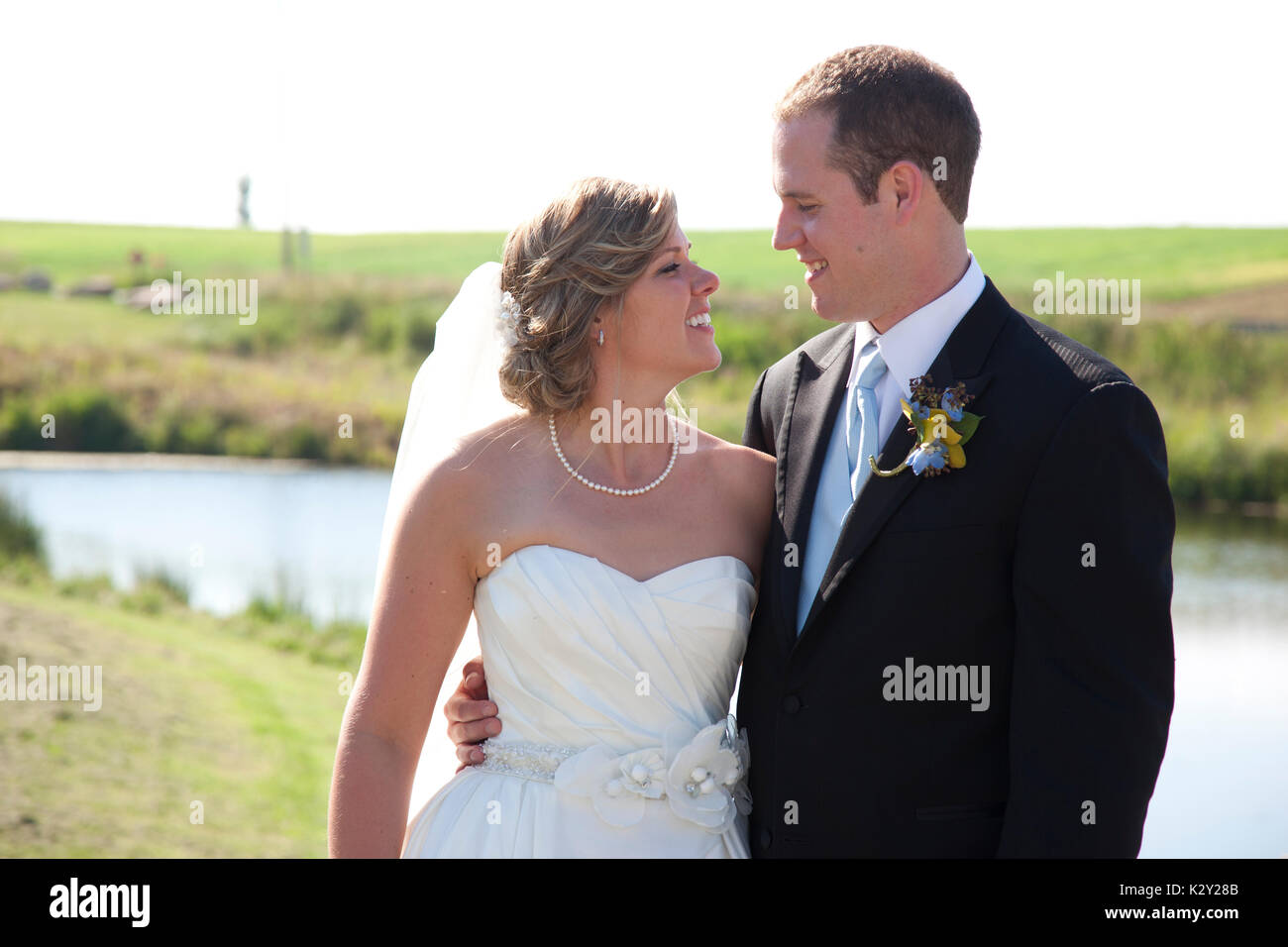 beautiful bride and handsome groom grin at each other outside in the ...
