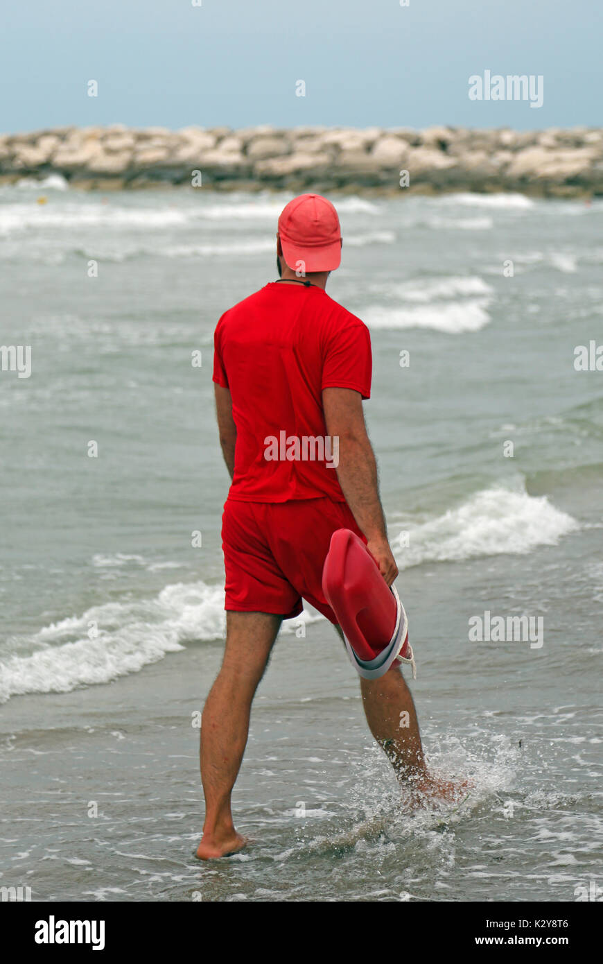 muscular lifeguard with red uniform checking the coast during storm ...