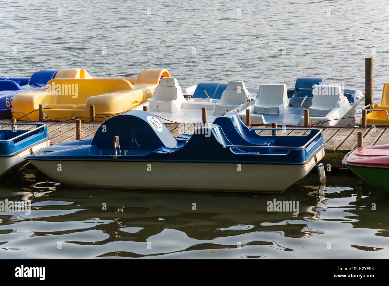 Colorful pedal boats at a wooden pier on a lake Stock Photo - Alamy