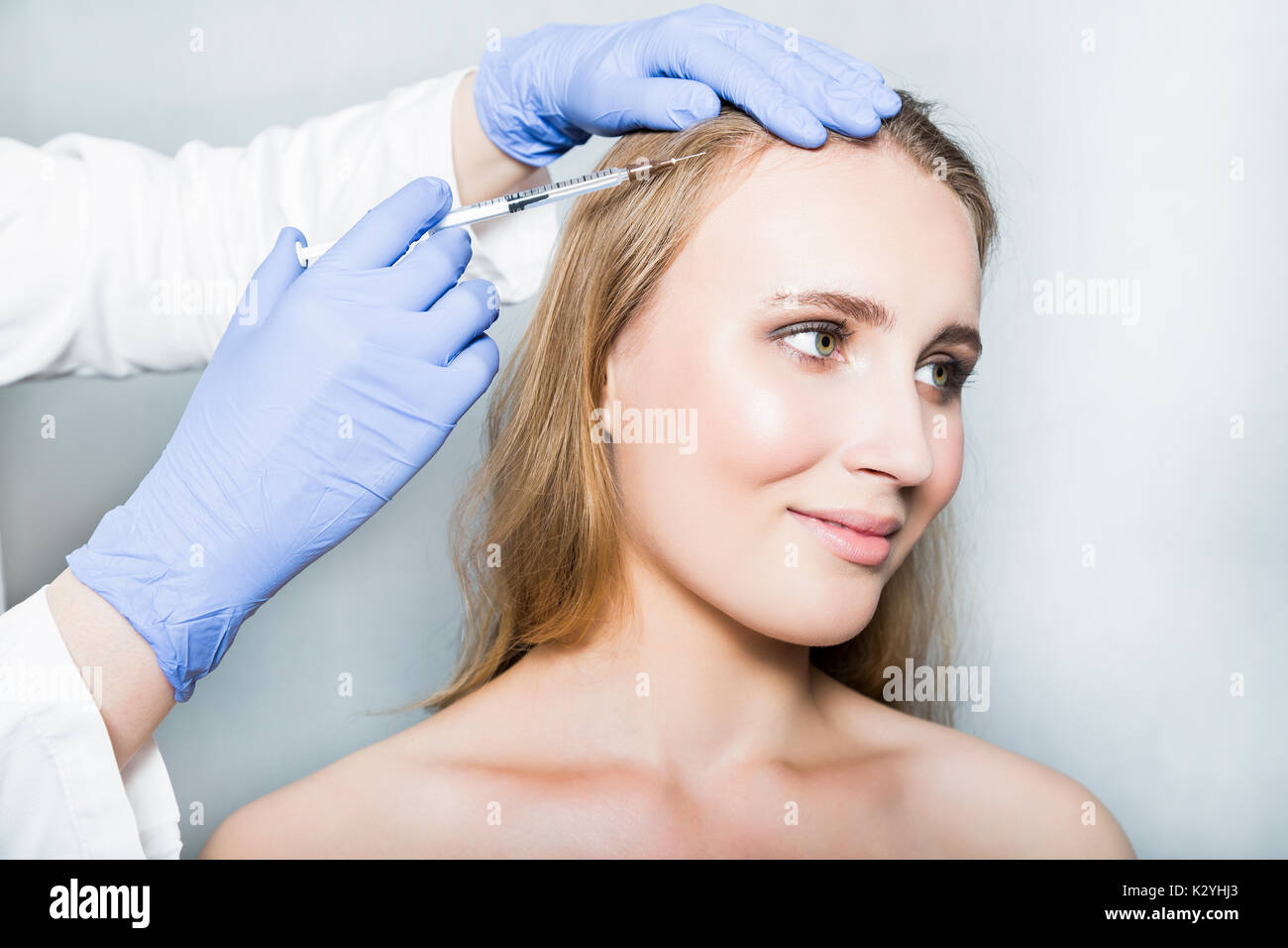 Doctor aesthetician with blue medical gloves and white medical gown ...