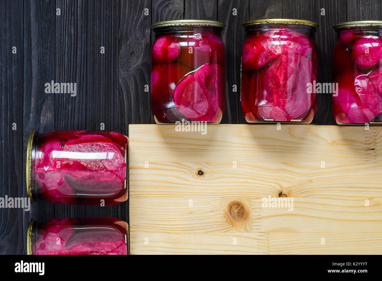 Canned homemade beetroot in clear glass jars with wooden cutting board ...
