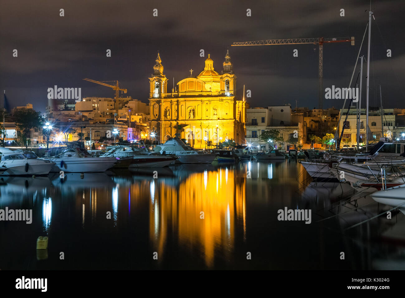 The beautiful Msida Parish Church at deep night with harbor at the ...