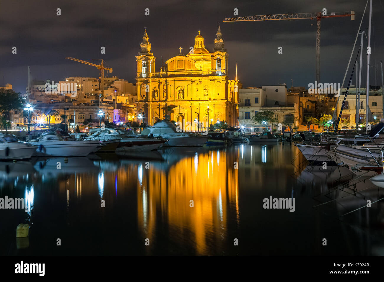 The beautiful Msida Parish Church at deep night with harbor at the ...