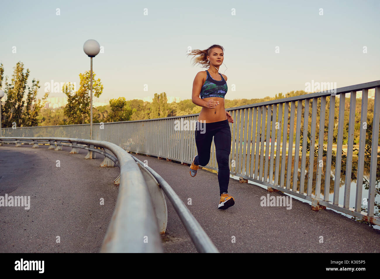 A woman runner jogs on a bridge in the city Stock Photo - Alamy
