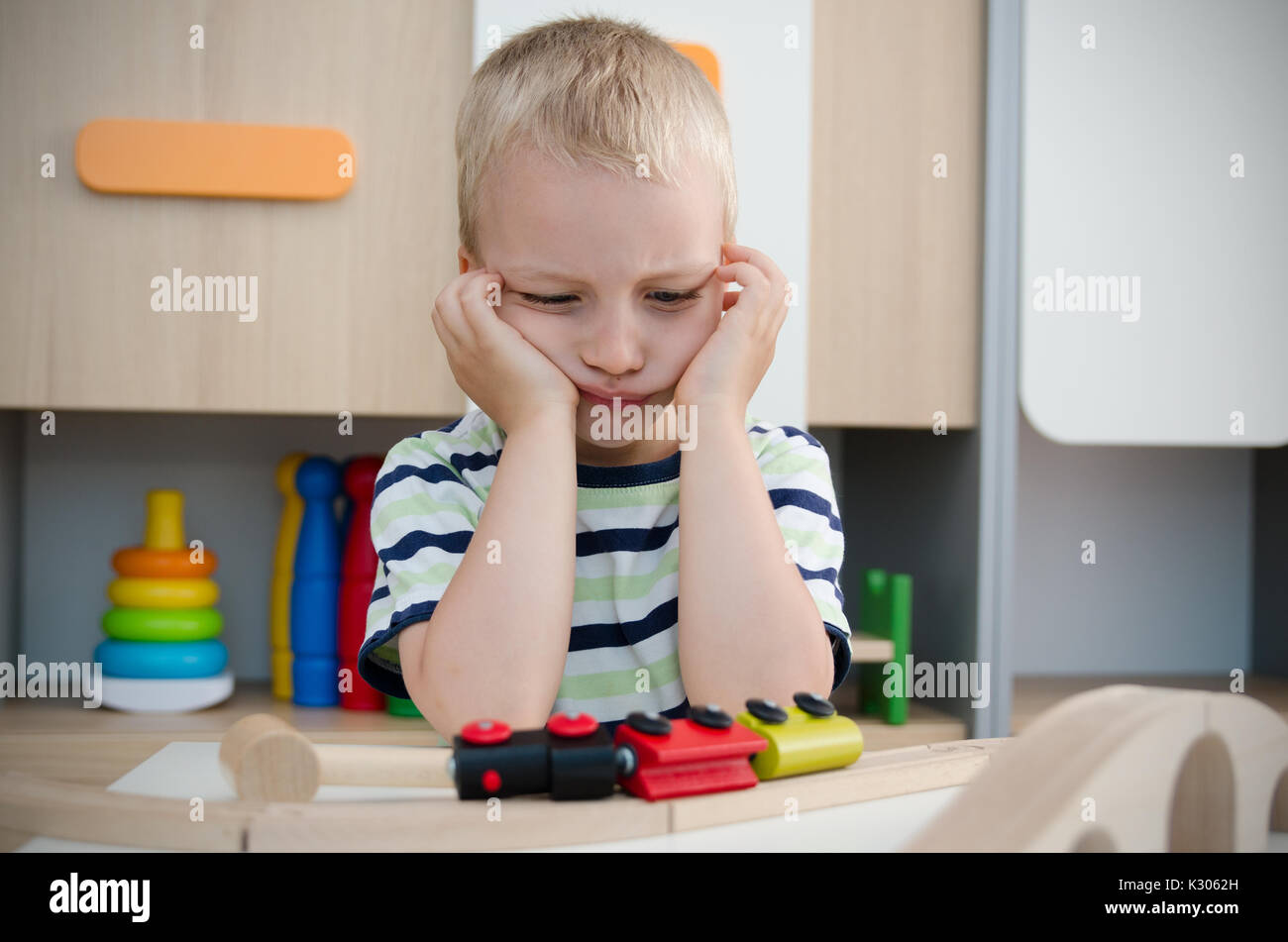 Bored sad little boy sitting at table. sad bored boy child toy activity ...