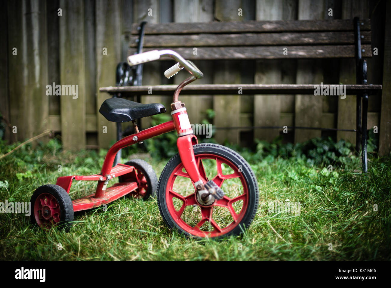 A children's trycicle is ready for play as it rests beside a wooden ...