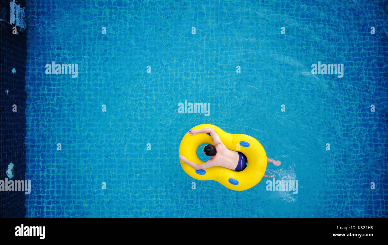 Top view, a man relaxing on yellow swim pool float, on swimming pool in ...