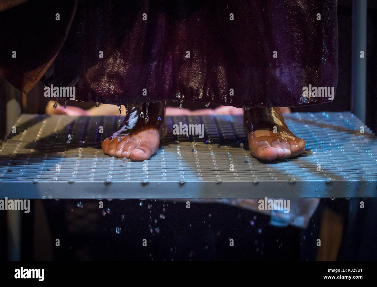 A person in a baptism robe drips water just after being baptized Stock ...