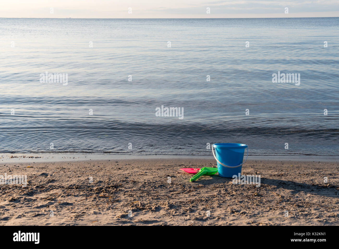 Sand beach with colorful plastic bucket and spades Stock Photo - Alamy
