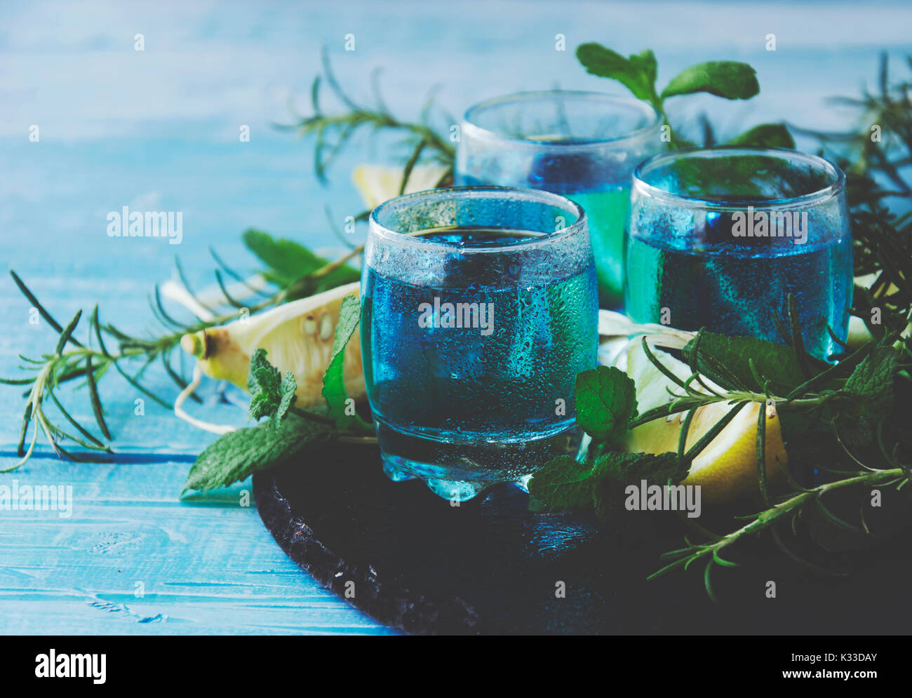 Blue curacao liqueur or sambuca with lemon on the wooden table ...