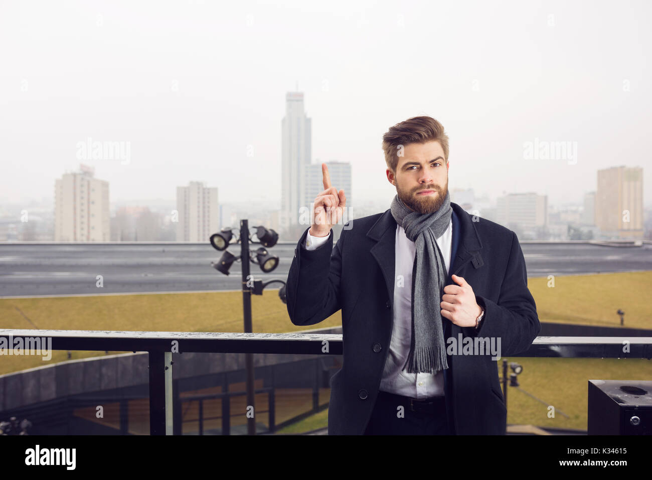 A photo of young, handsome man standing somewhere outside against urban ...