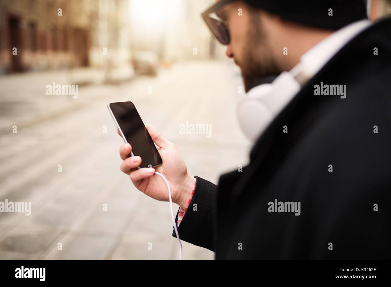A photo of young man looking at his reflection in the mobile phone ...