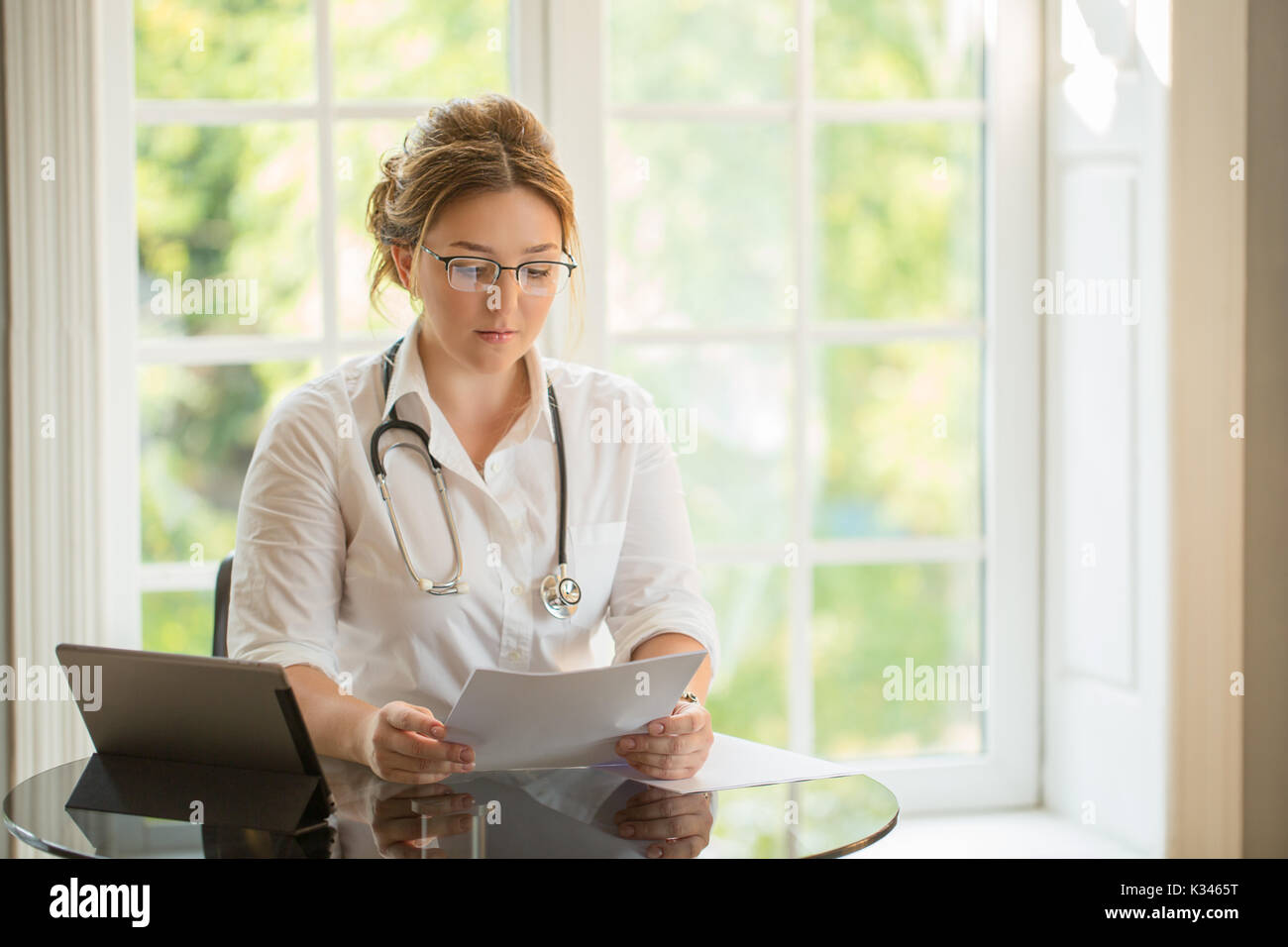 The woman young medical doctor seating at the table with stethoscope ...