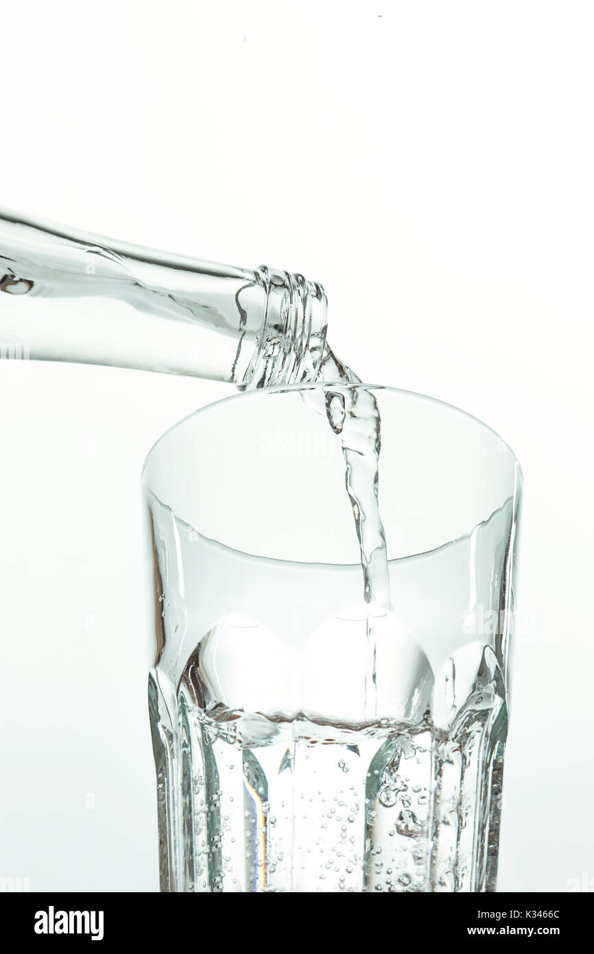 Pouring water from bottle into glass on white Stock Photo - Alamy