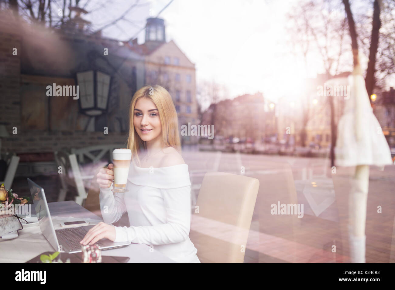 A photo of young, beautiful woman having coffee break during work. She ...