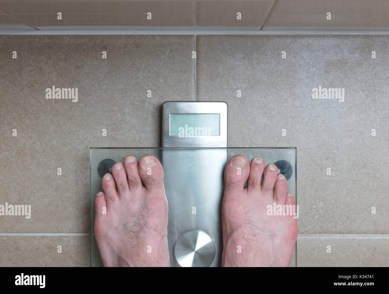 Closeup of man's feet on weight scale Stock Photo - Alamy