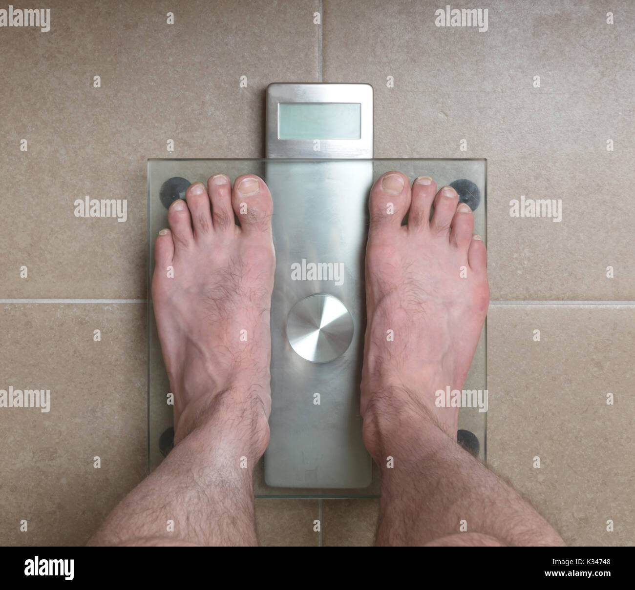 Closeup of man's feet on weight scale Stock Photo - Alamy