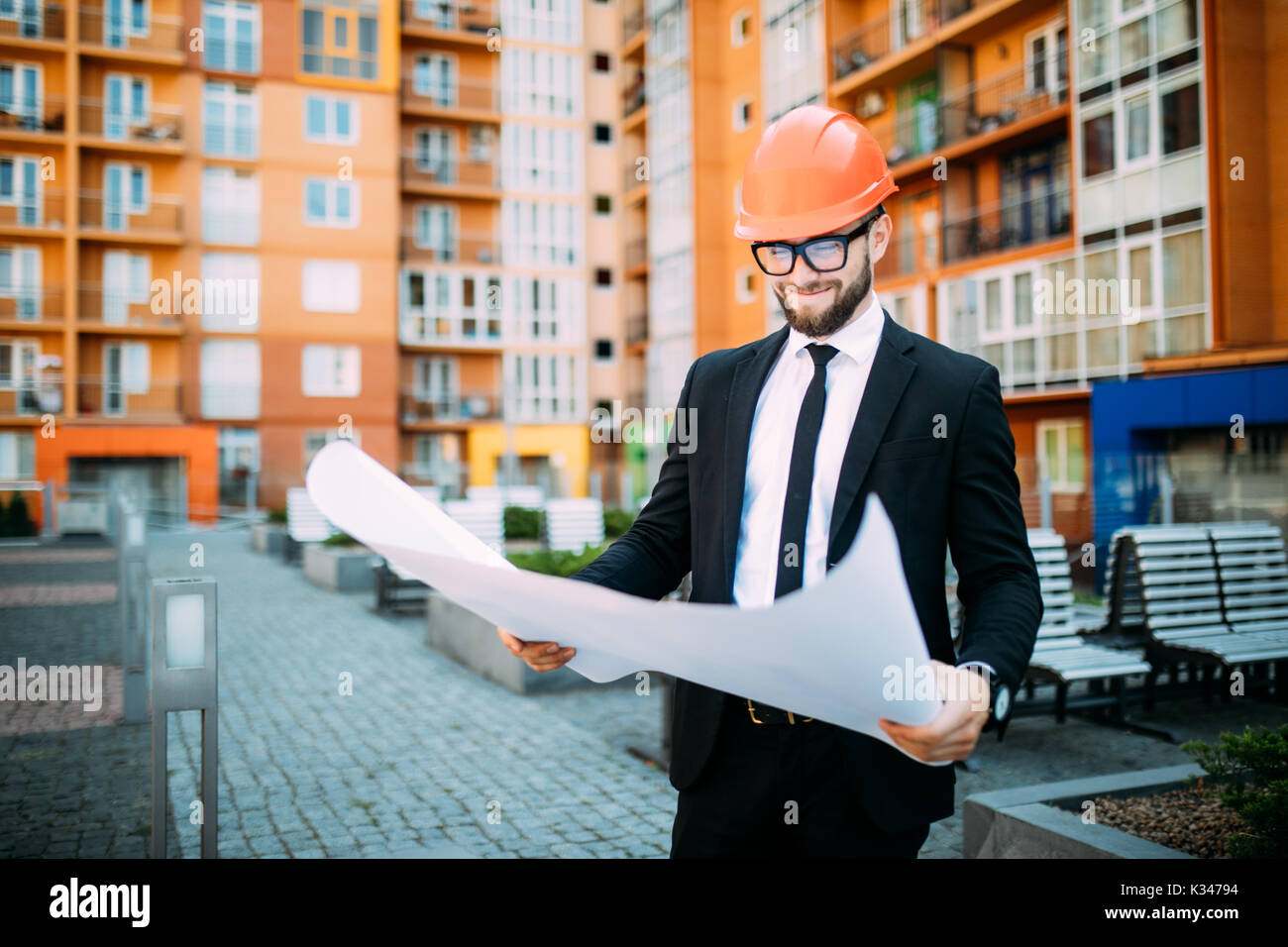 Engineer in front of modern building with plan Stock Photo - Alamy