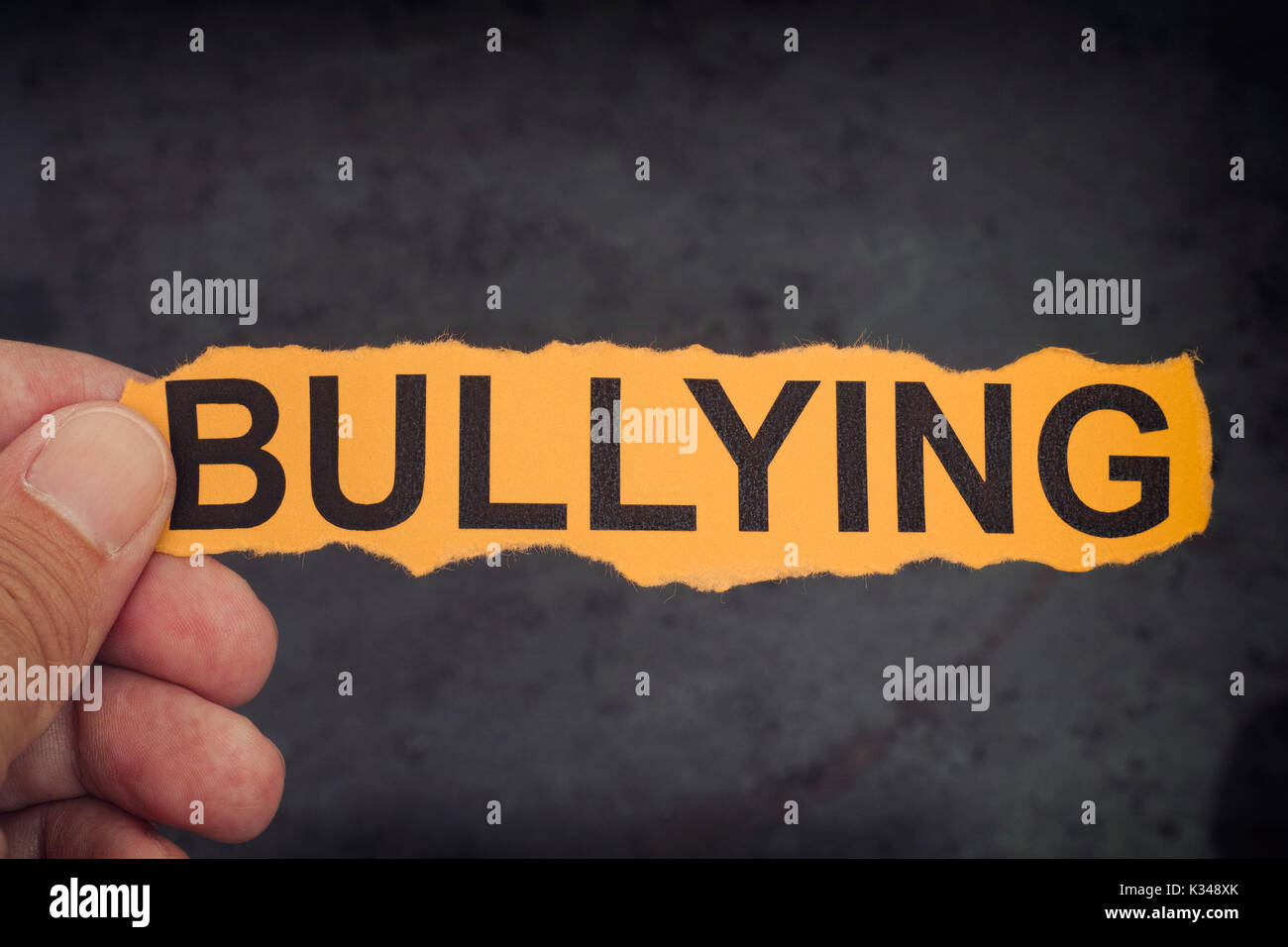 Person holds piece of paper with word Bullying in his hand. Close up ...