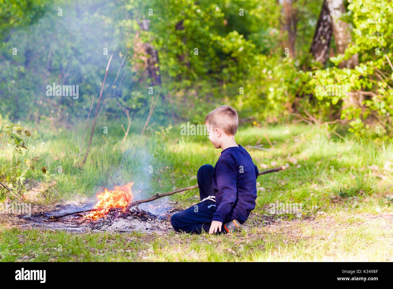 Little boy child in forest playing with bonfire Stock Photo - Alamy