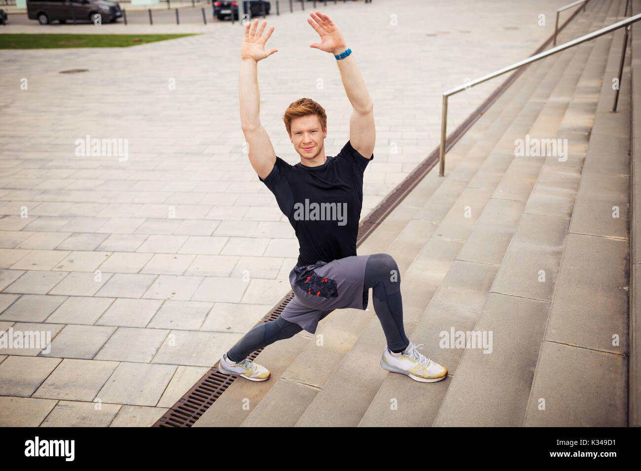 A photo of young, muscular man doing stretching exercises outdoors ...