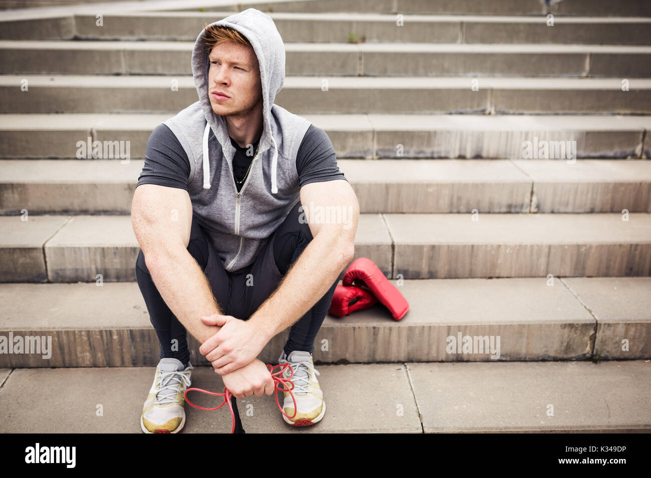 A photo of young man sitting on the stairs and taking a break during ...
