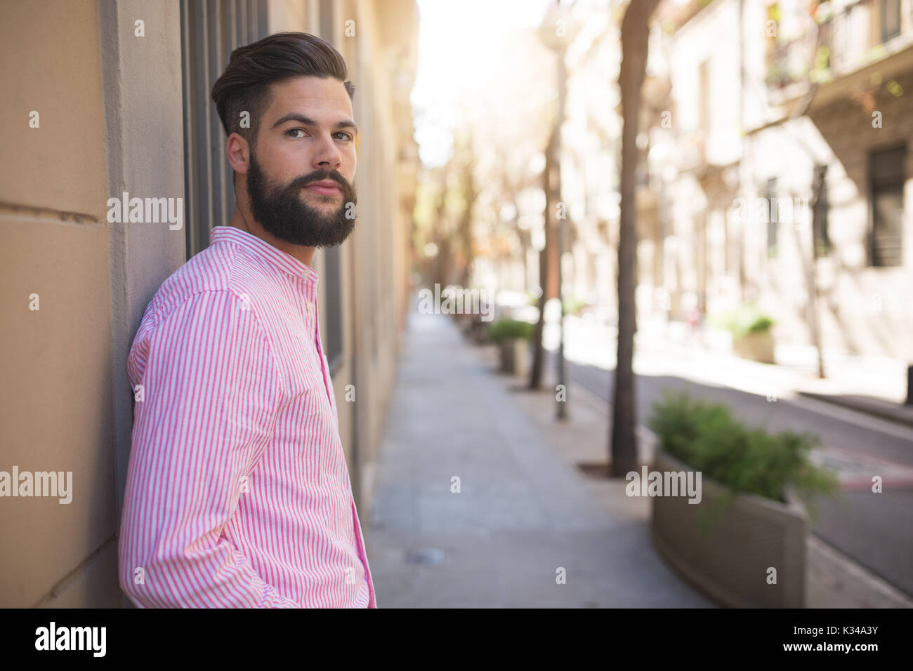 A photo of young man leaning against wall of some building and looking ...