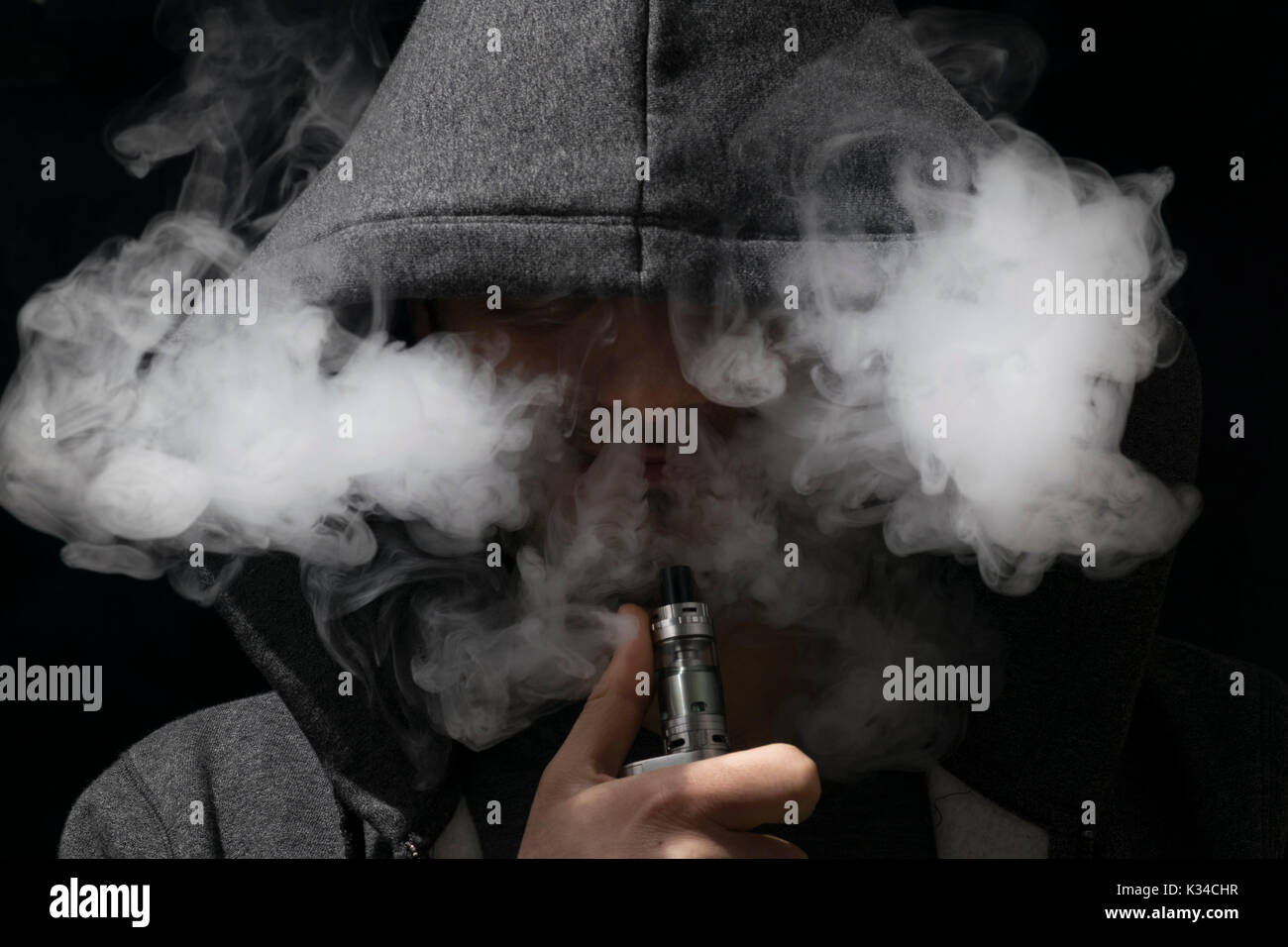 young man vaping electronic cigarette, holding a vape device with lots ...