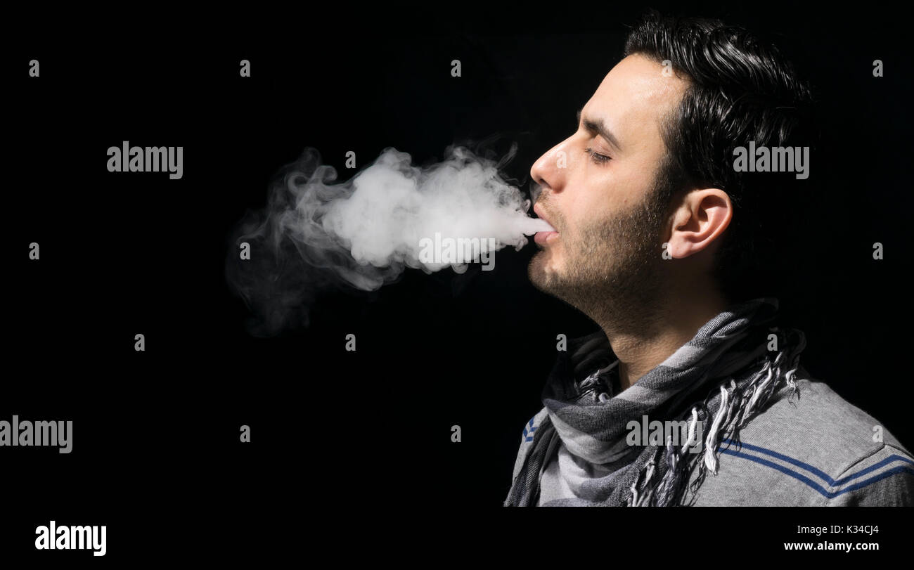 young man vaping electronic cigarette, holding a vape device with lots ...