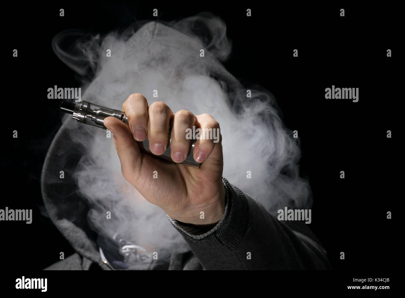 young man vaping electronic cigarette, holding a vape device with lots ...