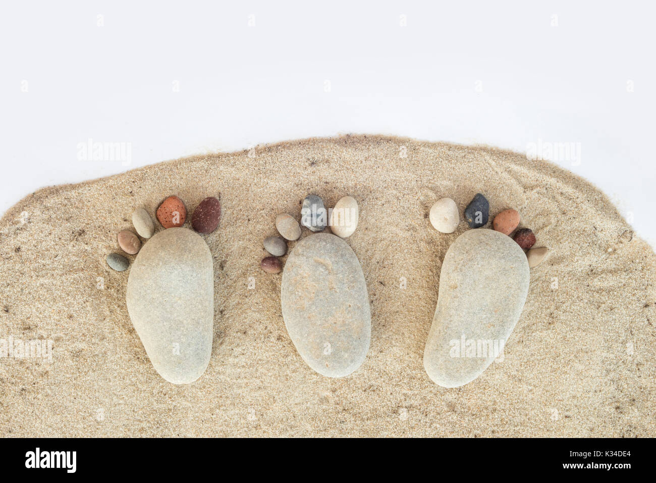 Group of pebble stones on sand creating de form of a foot in isolated ...