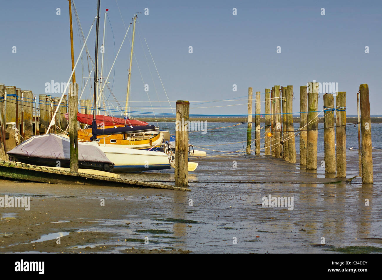 Small tidal harbour at low tide with various sailboats between mooring ...
