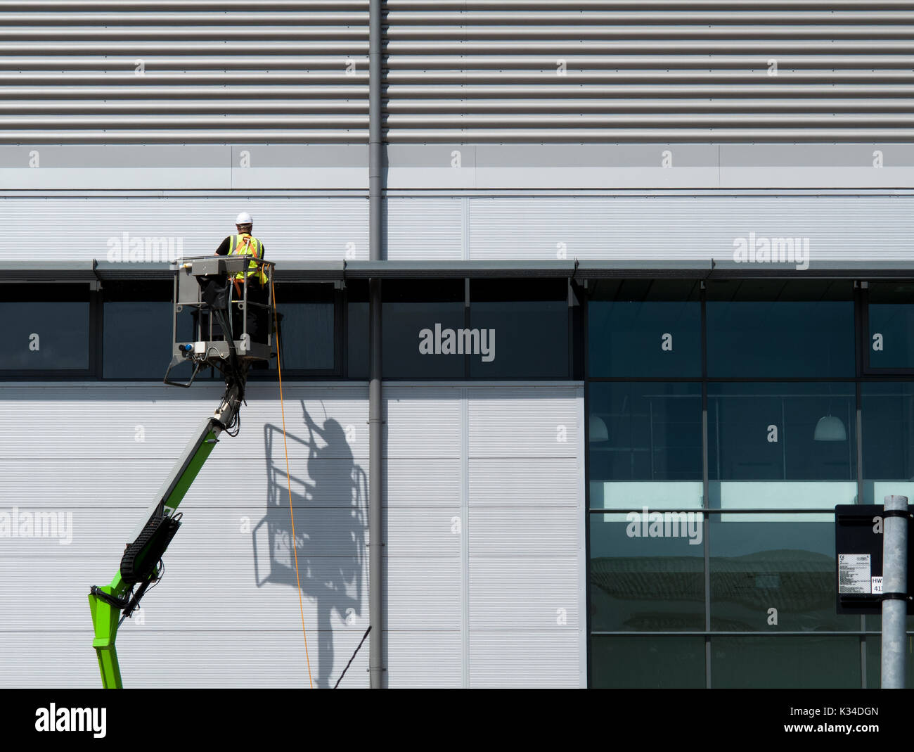 Construction worker on mobile boom lift cleaning external rainscreen ...