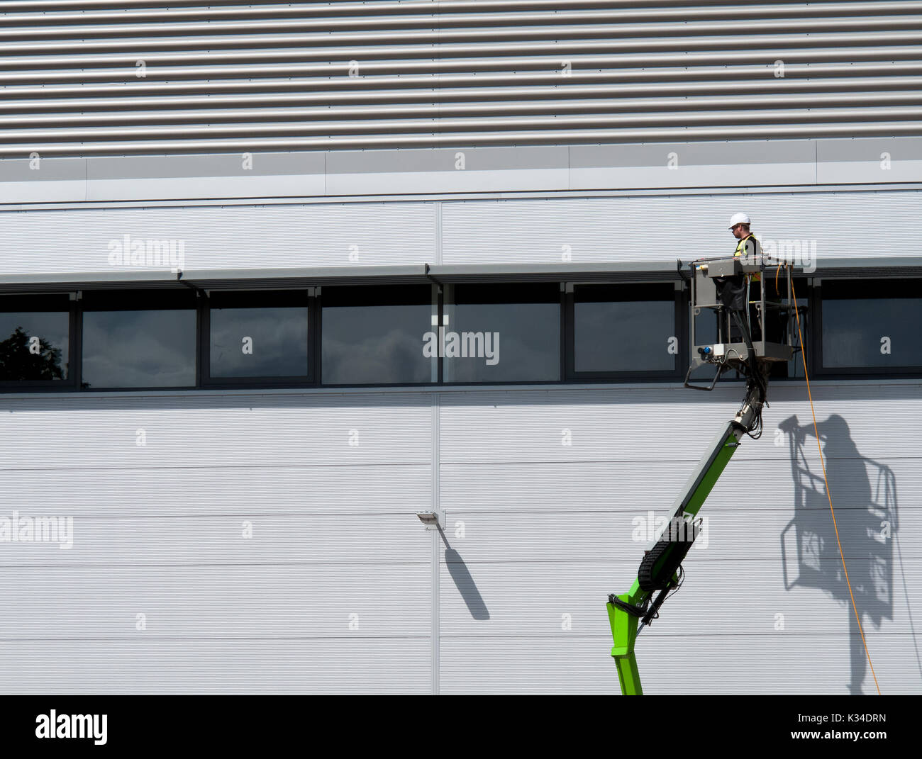 Construction worker on mobile boom lift cleaning external rainscreen ...